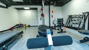 Uma academia com equipamentos de ginástica, esteira e banco de musculação.