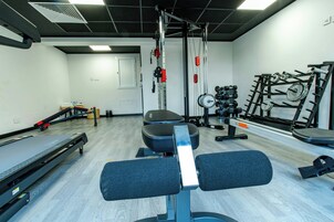 Uma academia com equipamentos de ginástica, esteira e banco de musculação.