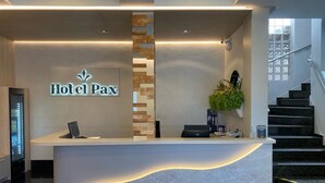 Bancada de recepção de hotel com design moderno, um letreiro indicando 