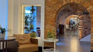 Um lobby moderno com arco de tijolos, assentos de couro e uma mesa de vidro com revistas.