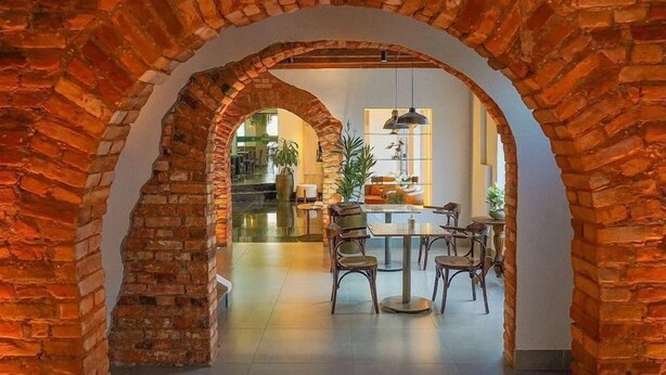 Uma área de refeições com um arco de tijolos, uma mesa redonda e cadeiras.