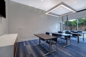 Uma sala de conferências com uma mesa comprida, cadeiras e piso coberto de carpete.