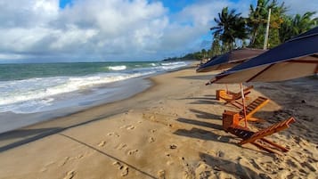 Na praia, areia branca, guarda-sóis