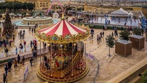 Um carrossel em uma praça pública com uma roda-gigante ao fundo.