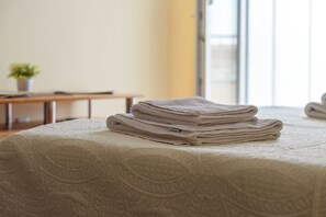 Um conjunto de toalhas dobradas em uma cama com um cobertor texturizado.
