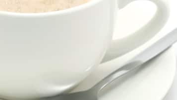 Uma chávena de café branca com uma colher sobre o pires.