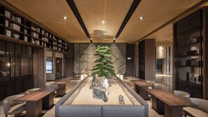 Um interior moderno com uma mesa de jantar comprida, cadeiras e um bonsai como peça central.
