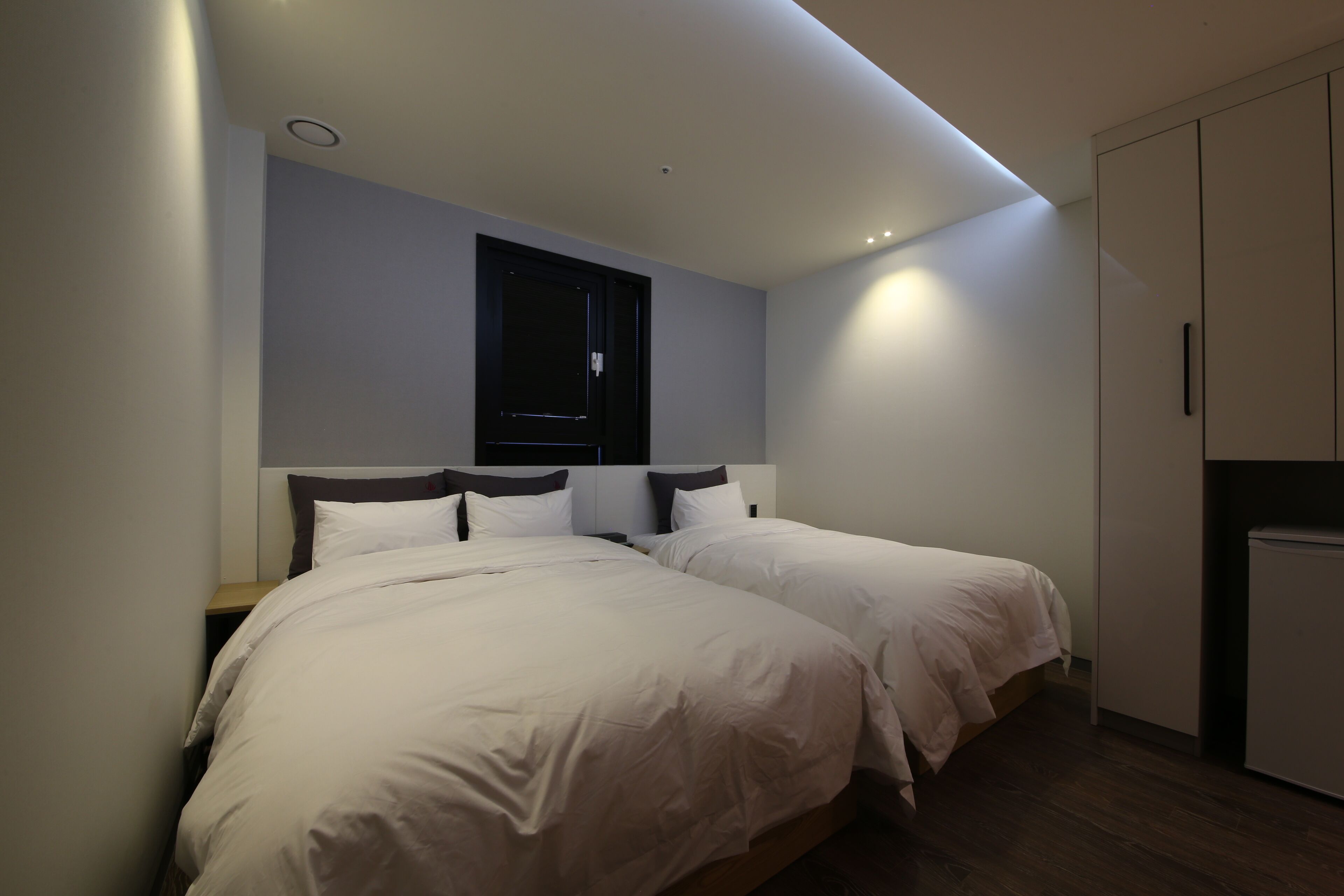 Quarto com duas camas, um guarda-roupa e uma kitchenette pequena.