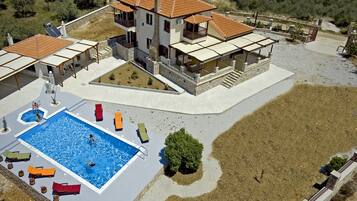 Uma casa de dois andares com piscina, área de estar externa e jardim.