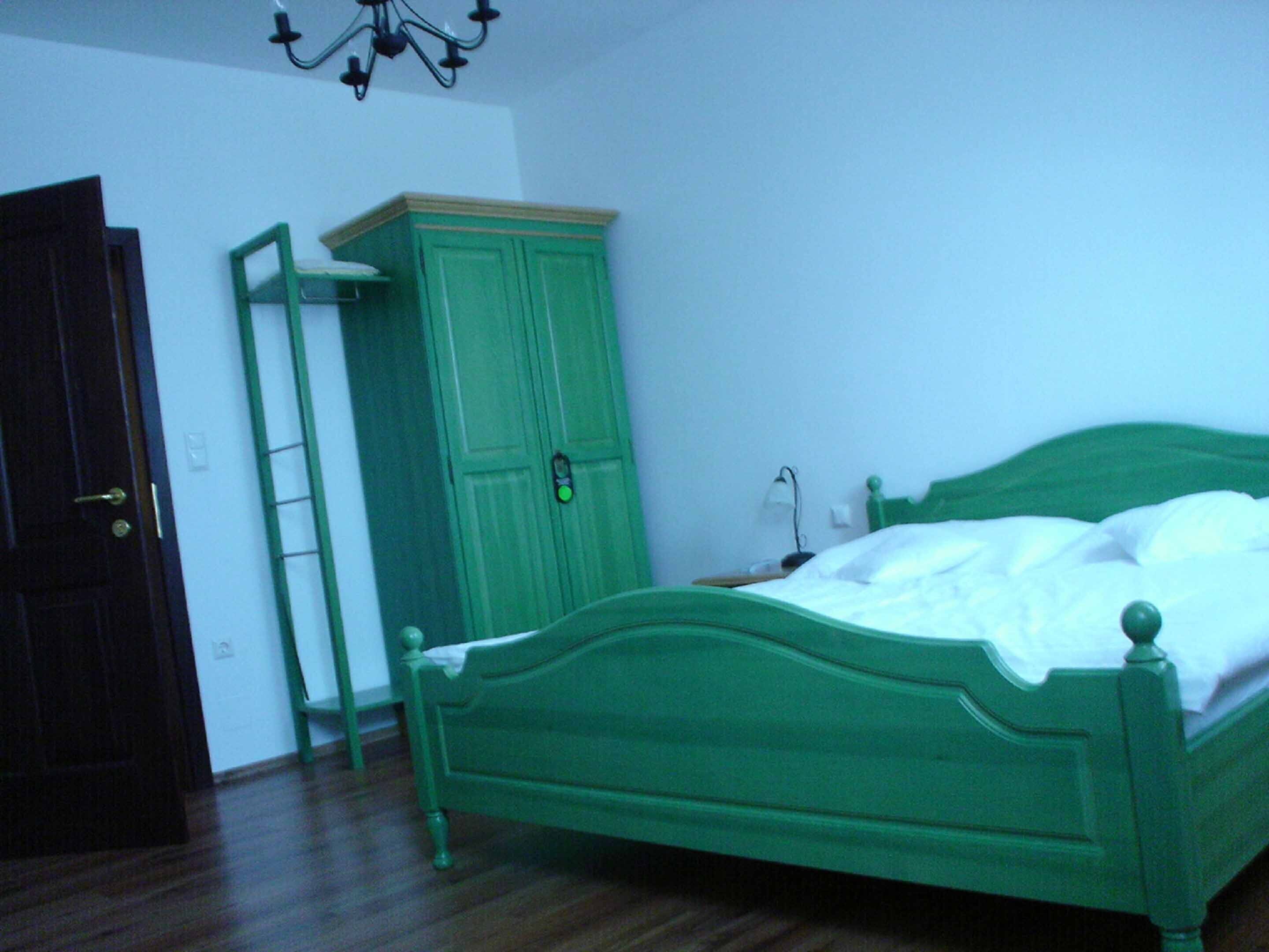 Quarto com cama verde, guarda-roupa e porta.