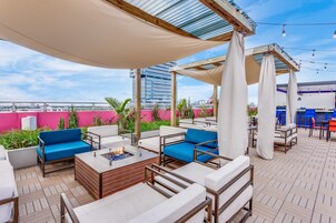 Um terraço com área de estar ao ar livre, lareira e vista para o horizonte da cidade.
