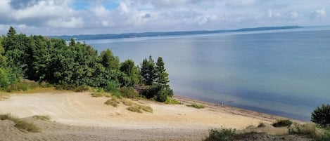 Uma praia com vista clara para o mar e terra ao longe, cercada por árvores.