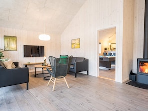 Uma sala de estar aconchegante com lareira, sofá, poltrona e televisão.