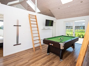 Quarto moderno com mesa de bilhar, televisão na parede e uma grande janela com vista para o exterior.