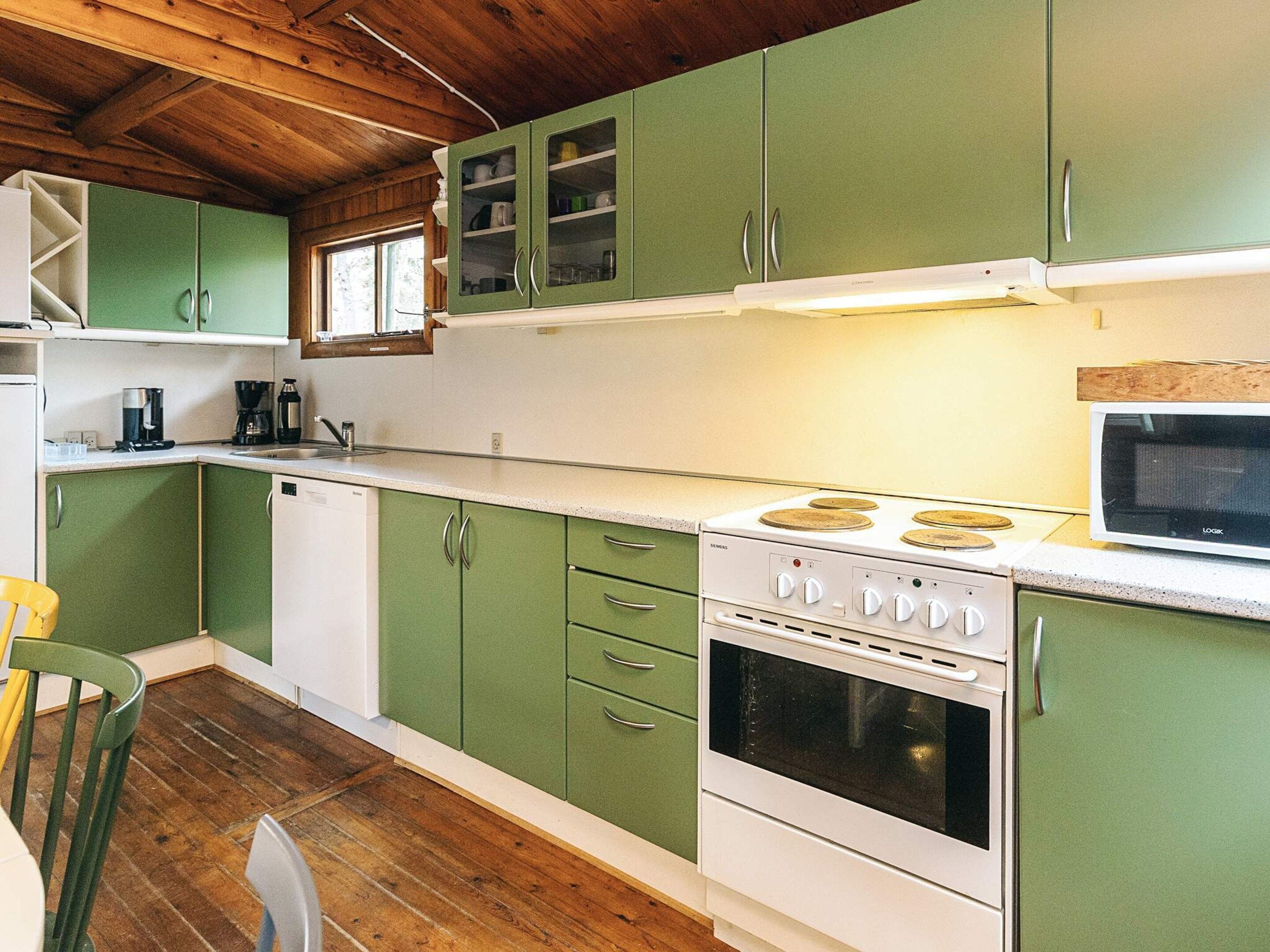 Uma cozinha com armários verdes, um fogão branco e um micro-ondas.