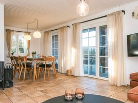 Uma sala de jantar com uma mesa, cadeiras, lareira e TV na parede.