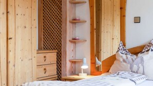 Quarto de madeira com cama, mesa de cabeceira, cômoda e espelho.