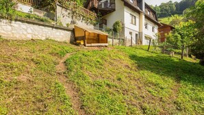 Uma casa de dois andares com varanda, alpendre coberto e parede de pedra.