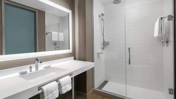 Casa de banho moderna com lavatório branco, espelho e cabine de duche em vidro.