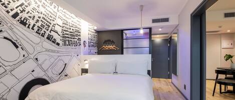 Quarto de hotel moderno com uma cama grande, um mapa na parede, uma mesinha com uma cadeira e um cabideiro.