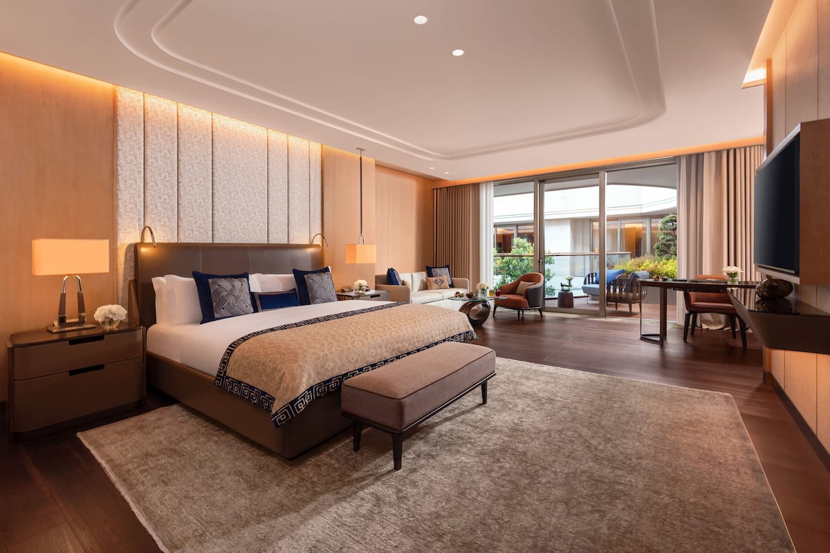 Quarto de hotel moderno com uma cama grande, uma escrivaninha e vista para o exterior.