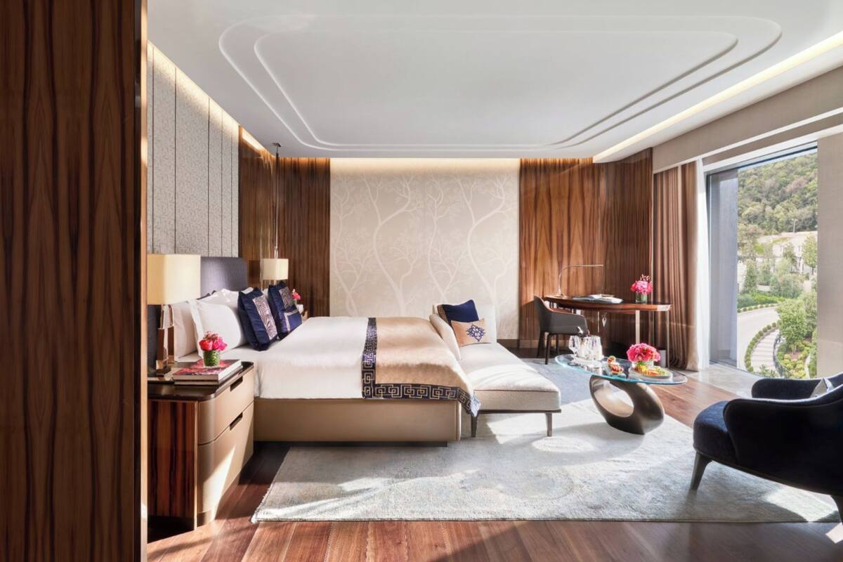 Quarto de hotel moderno com uma cama grande, uma escrivaninha e vista para o exterior.