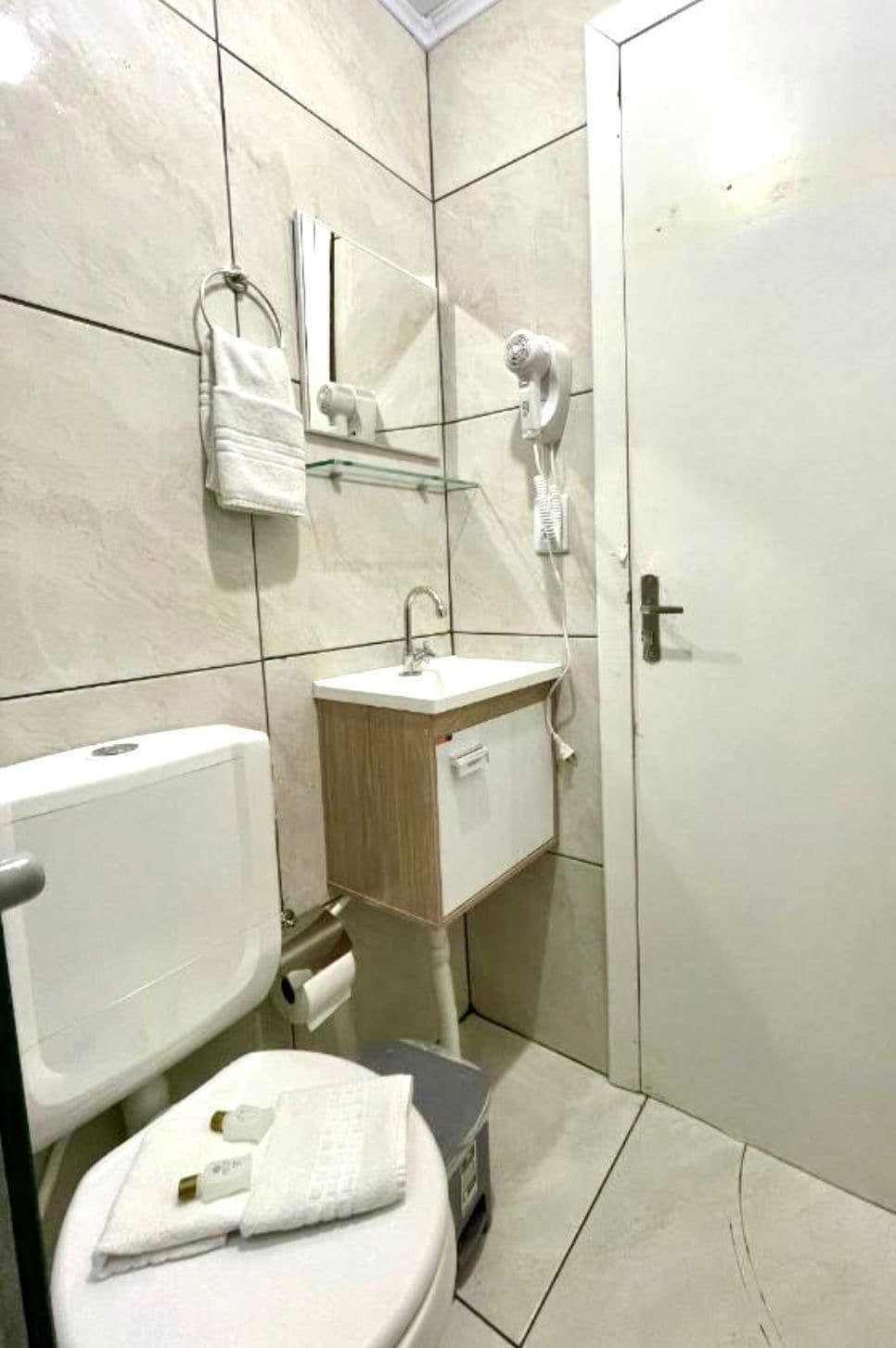 Casa de banho com sanita, lavatório e porta-toalhas.