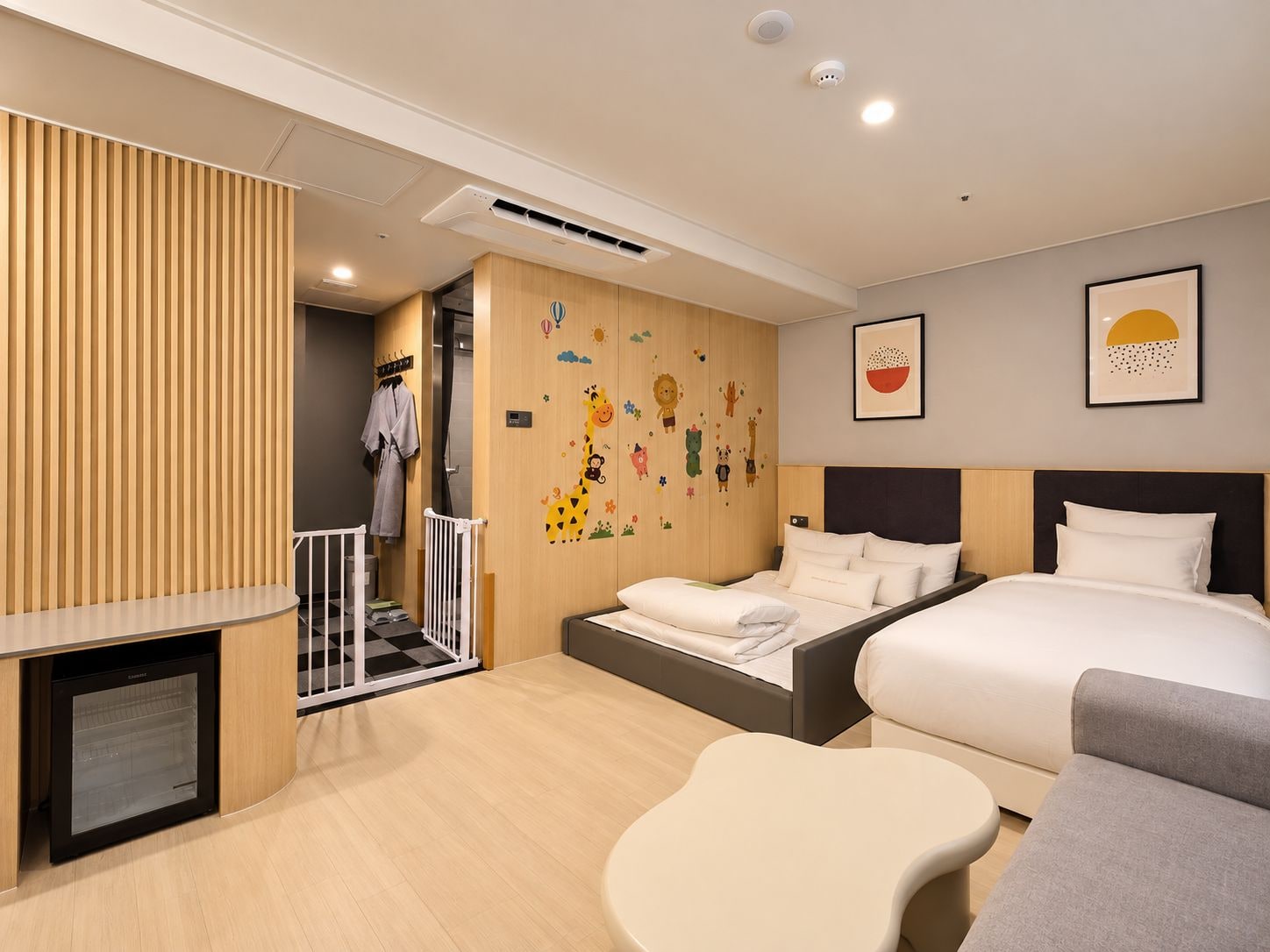 Quarto de hotel com cama, sofá, mesa pequena, armário e banheiro com chuveiro.