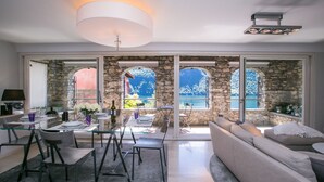 Uma sala de estar moderna com parede de pedra, mesa de jantar de vidro e um sofá.