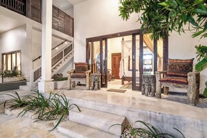 Interior espaçoso com escada, móveis de madeira e vista para um quarto com cama e cortinas.