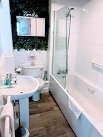 Casa de banho com cabine de duche em vidro, lavatório branco e sanita.