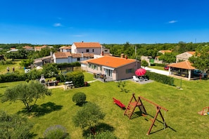 Um bairro residencial com casas, um pátio com guarda-sol vermelho e um balanço.