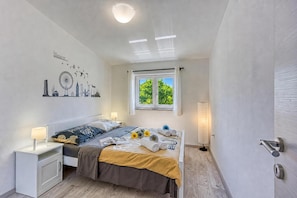 Quarto com cama, mesas de cabeceira, janela e arte de parede com vista urbana.
