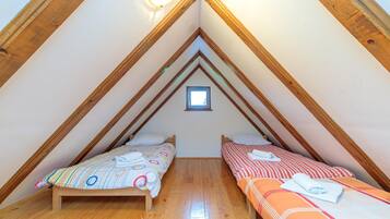 Um quarto de sótão pequeno com duas camas, vigas de madeira e um claraboia.