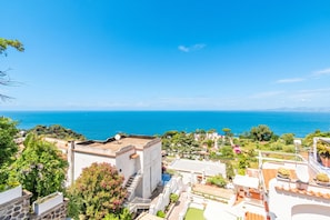 Zona residencial à beira-mar, com vista para o oceano, apresentando um edifício branco com varanda e jardim.