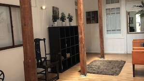 Uma sala de estar espaçosa com piso de madeira, um móvel para entretenimento preto e uma grande janela.