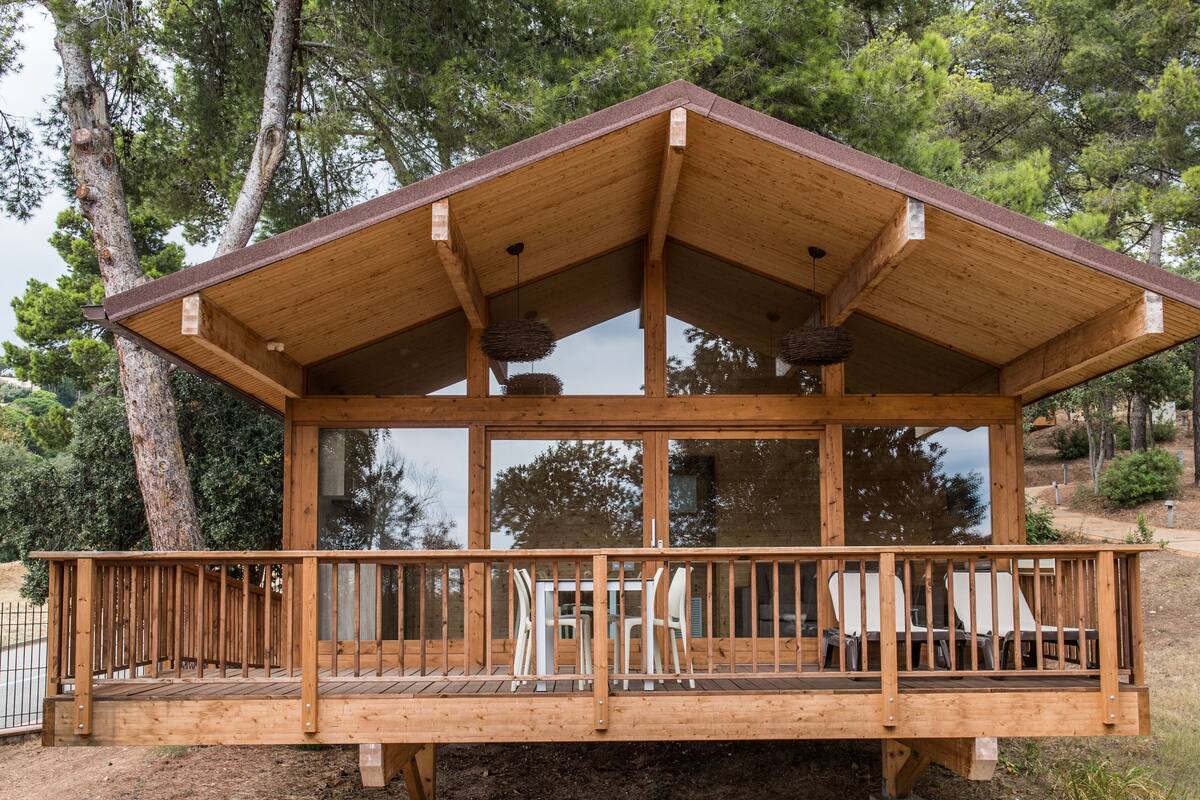 Um gazebo de madeira com cobertura, deck e assentos.