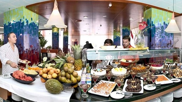 Buffet com diversos alimentos e uma variedade de frutas tropicais.