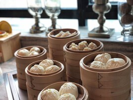 Uma mesa com vários cestos de bambu cheios de bolinhos brancos.