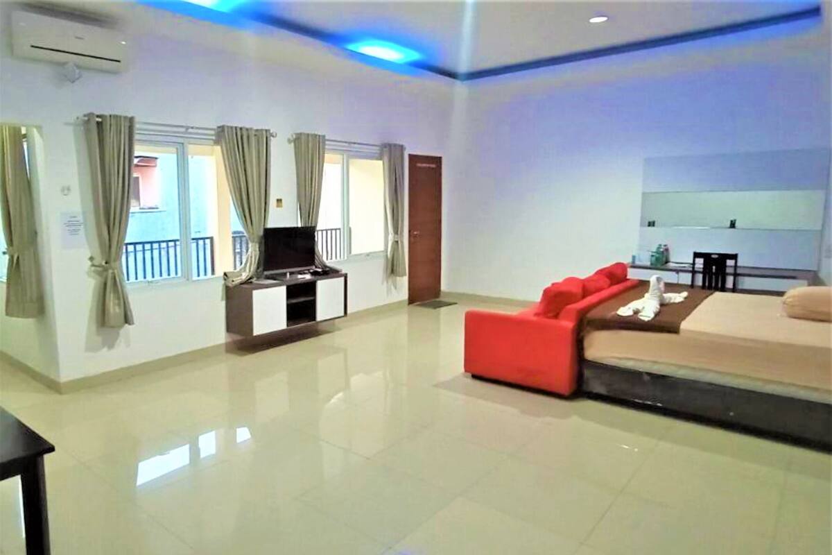 Uma sala de estar moderna com televisão de tela plana, um sofá vermelho e um espaço de refeições com mesa e cadeiras.