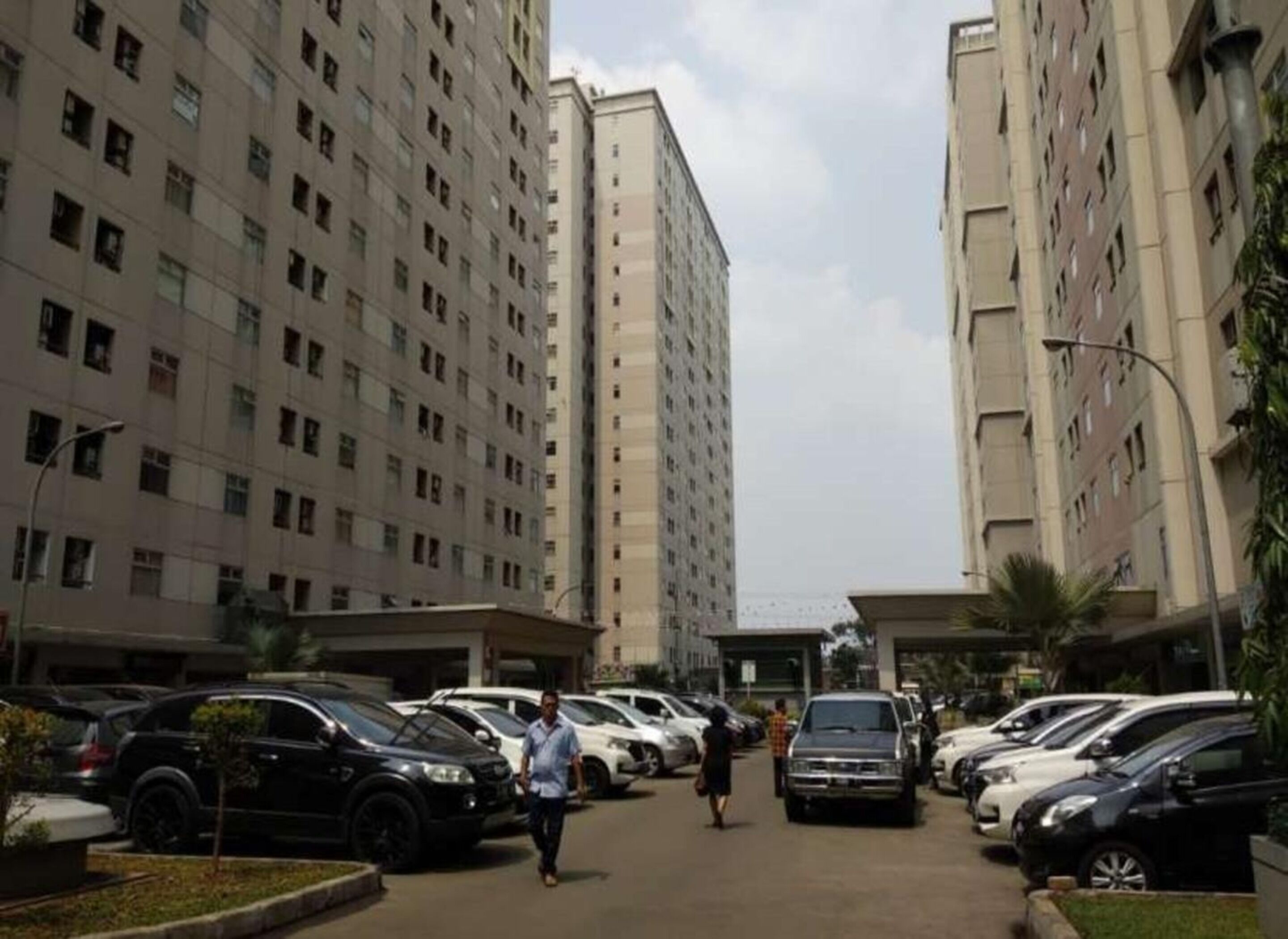 Um edifício residencial com vários andares e uma área de estacionamento na frente.