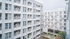 Um edifício residencial com vários andares, varandas, janelas amplas e aparelhos de ar condicionado.