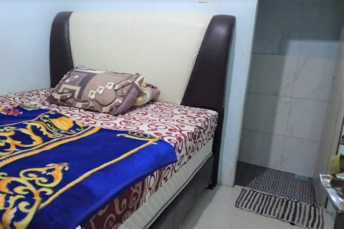 Uma cama com colcha estampada, travesseiros e cabeceira.