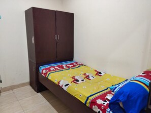 Quarto com uma cama de solteiro, guarda-roupa e chão em azulejos.
