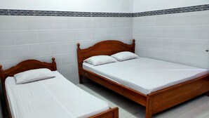 Duas camas de madeira com lençóis brancos em um quarto com paredes azulejadas e um detalhe decorativo.