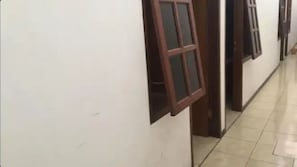 Um corredor com parede branca e porta com janela.