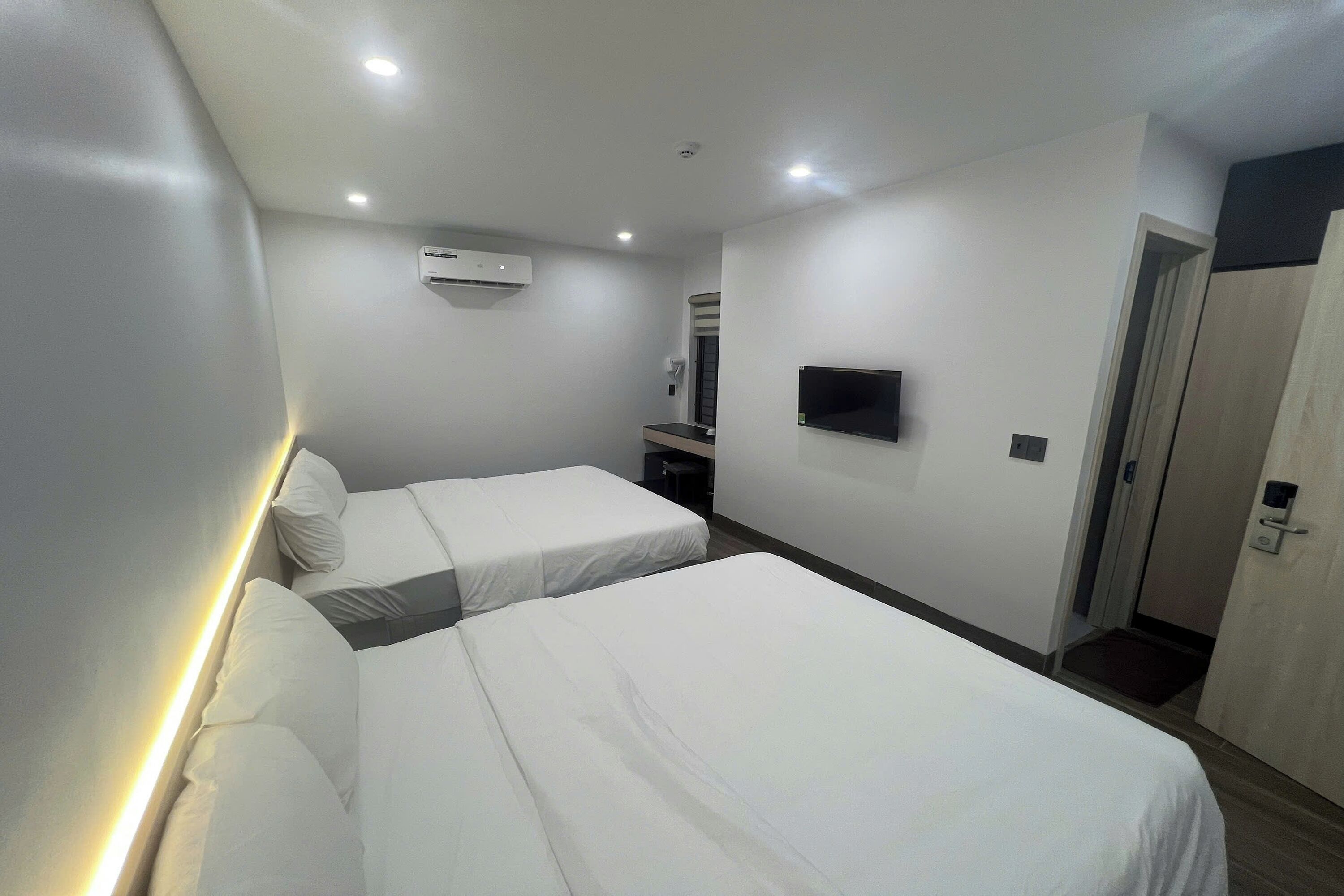 Quarto de hotel com duas camas, televisão de tela plana, ar condicionado e uma porta.