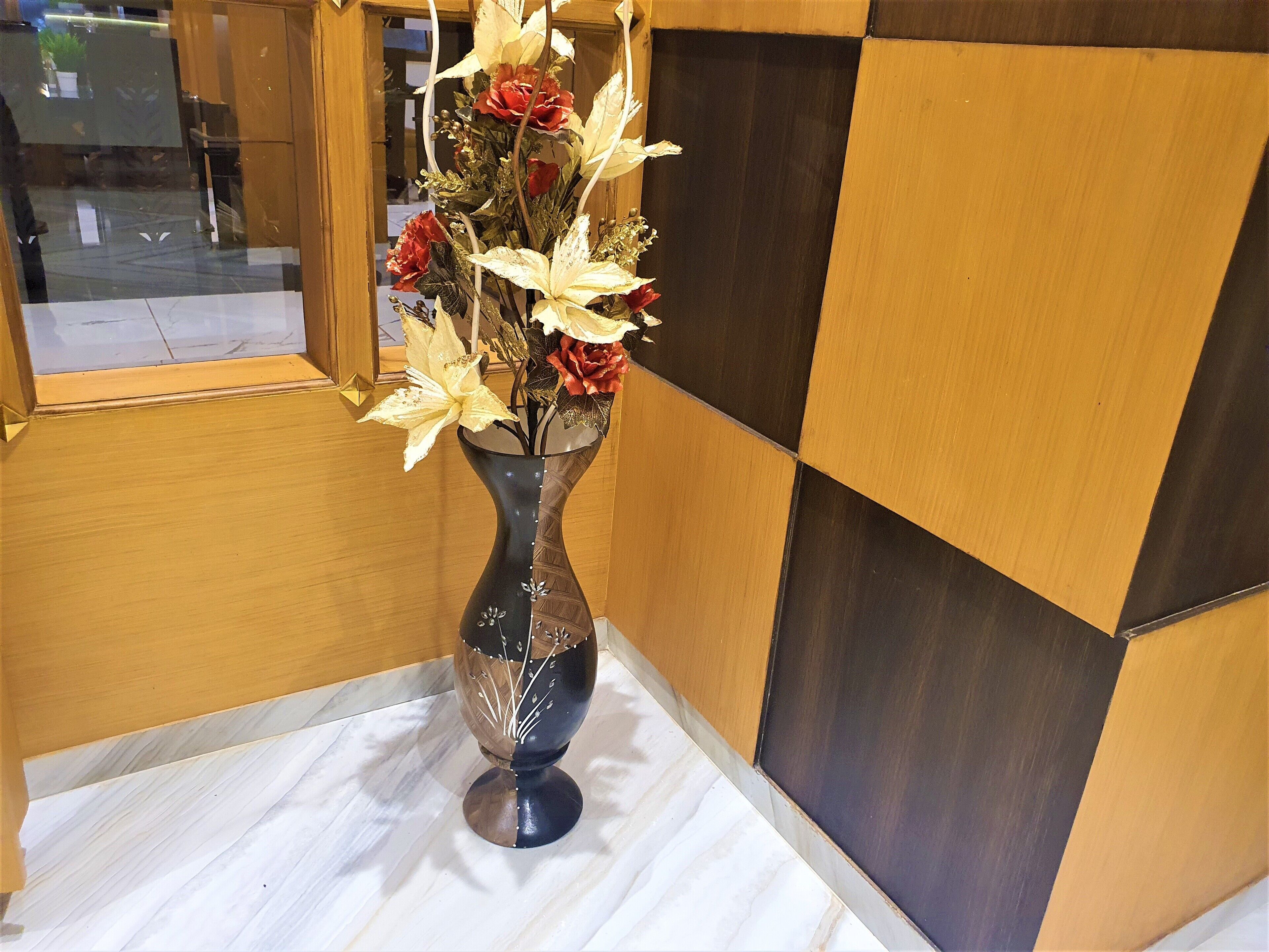 Um vaso com flores sobre um chão de azulejos brancos.