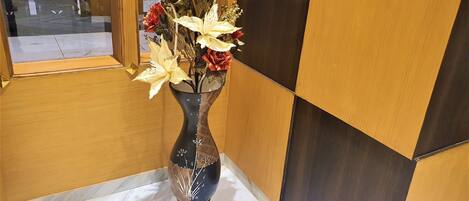 Um vaso com flores sobre um chão de azulejos brancos.