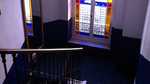 Uma escadaria com corrimão, espelho e porta com vitrais.